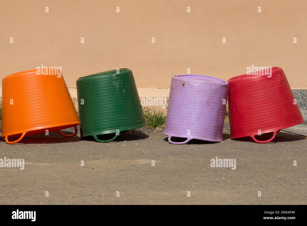 Four colored plastic containers lie upside down near the plastered wall ...