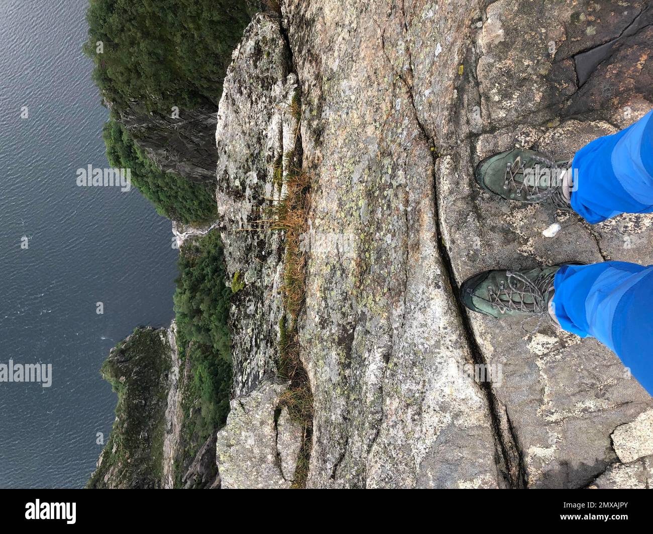 Feet in hiking boots, standing at a rocky outcrop, Preikestolen rock ...