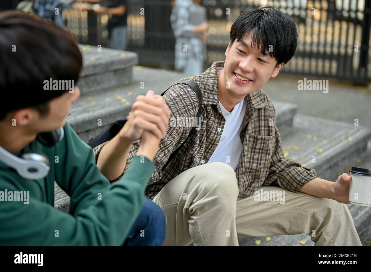Happy young Asian male college student having friendly handshake with ...