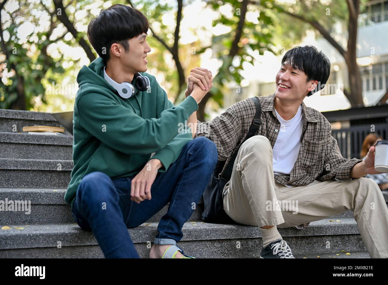 Happy and cheerful young Asian male college student having friendly ...