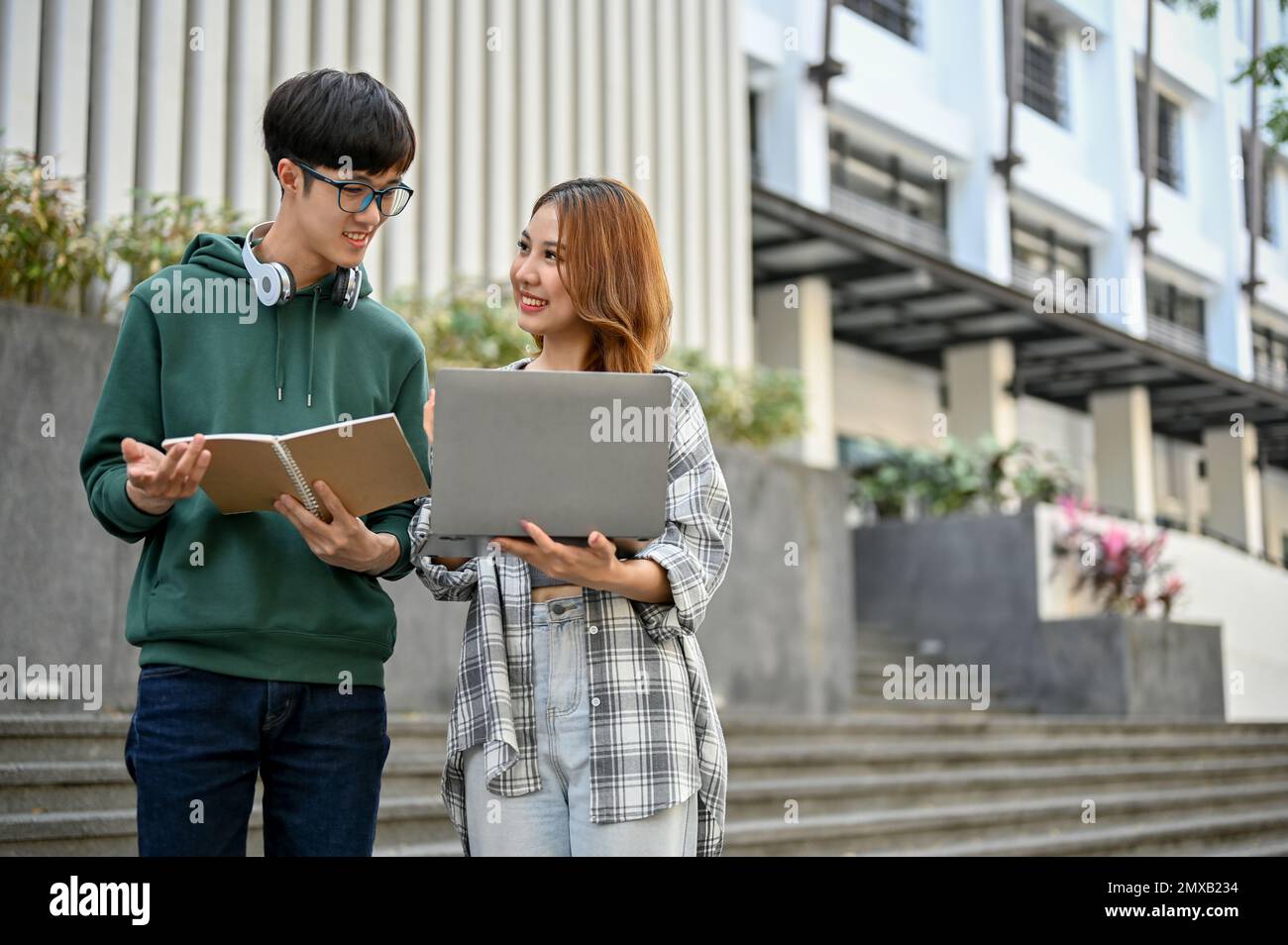 Happy and smiling young Asian college students are talking, working on their school project on ...