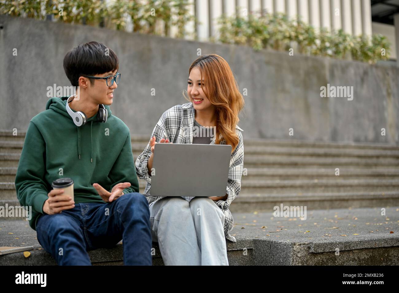 Happy and smiling young Asian college students are talking, working on their school project on ...