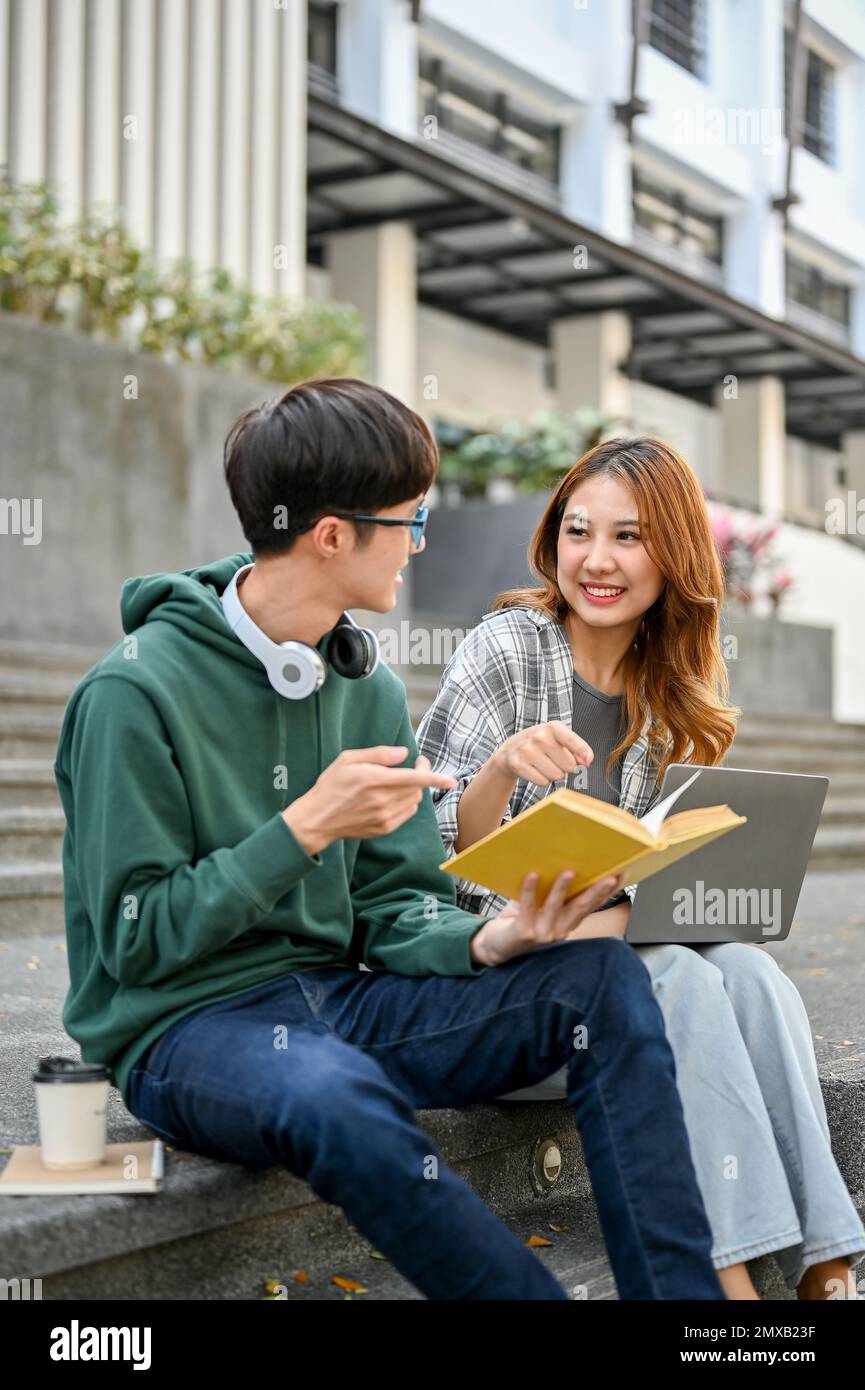 Cheerful young Asian college students are talking, sharing ideas, working on their school ...