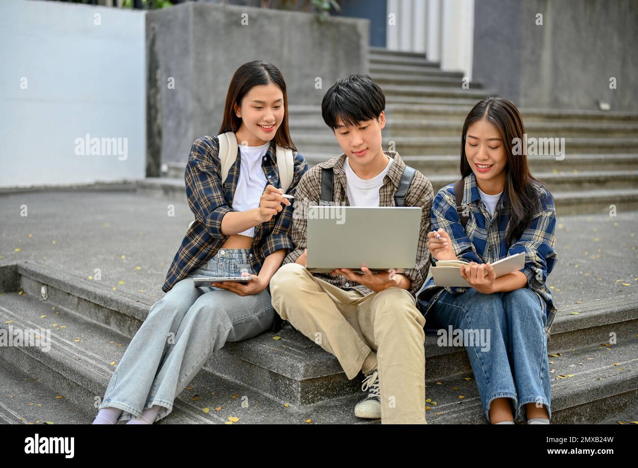Group of young Asian college students sitting on stairs in front of the ...
