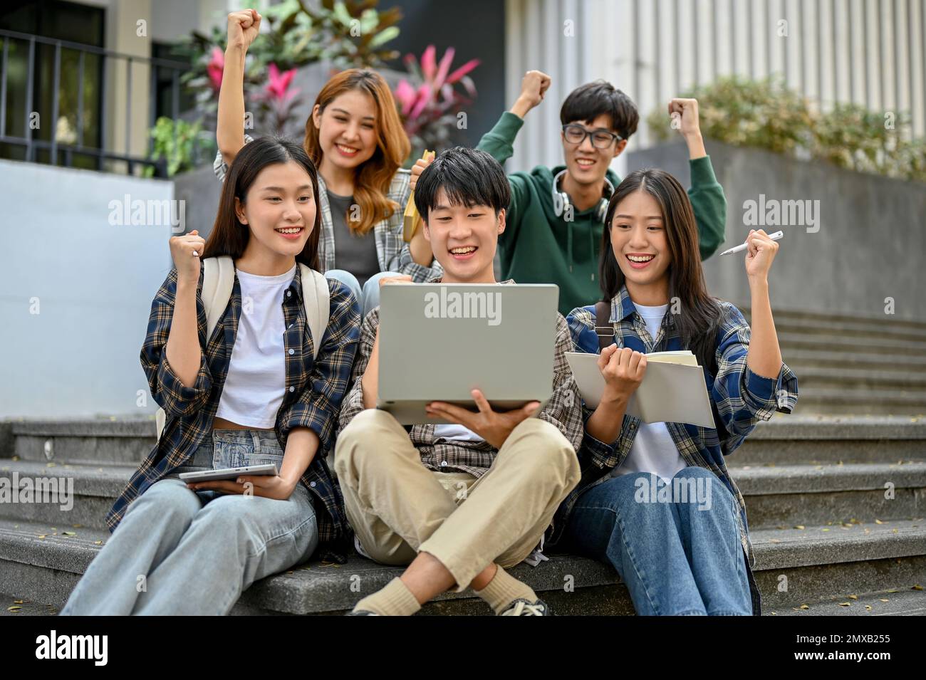 Group of cheerful young Asian college students sitting on stairs in ...
