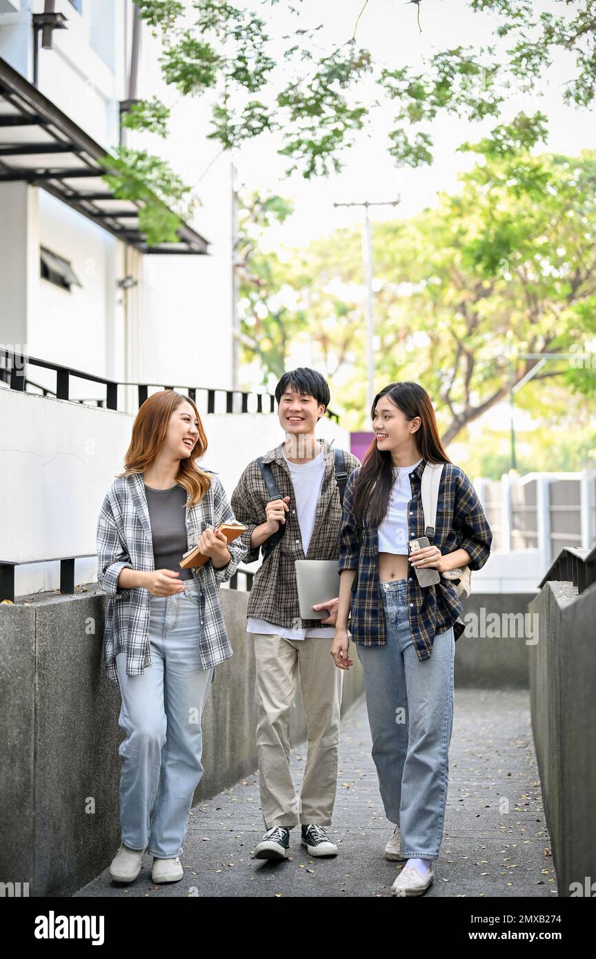 Group of happy and cheerful young Asian college students enjoy talking, laughing while walking ...
