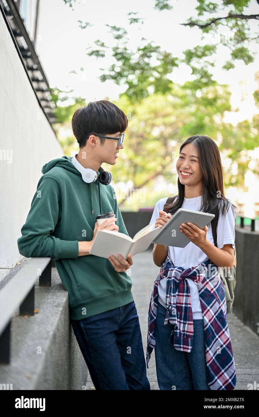 Happy young Asian college students talking and sharing ideas on a ...