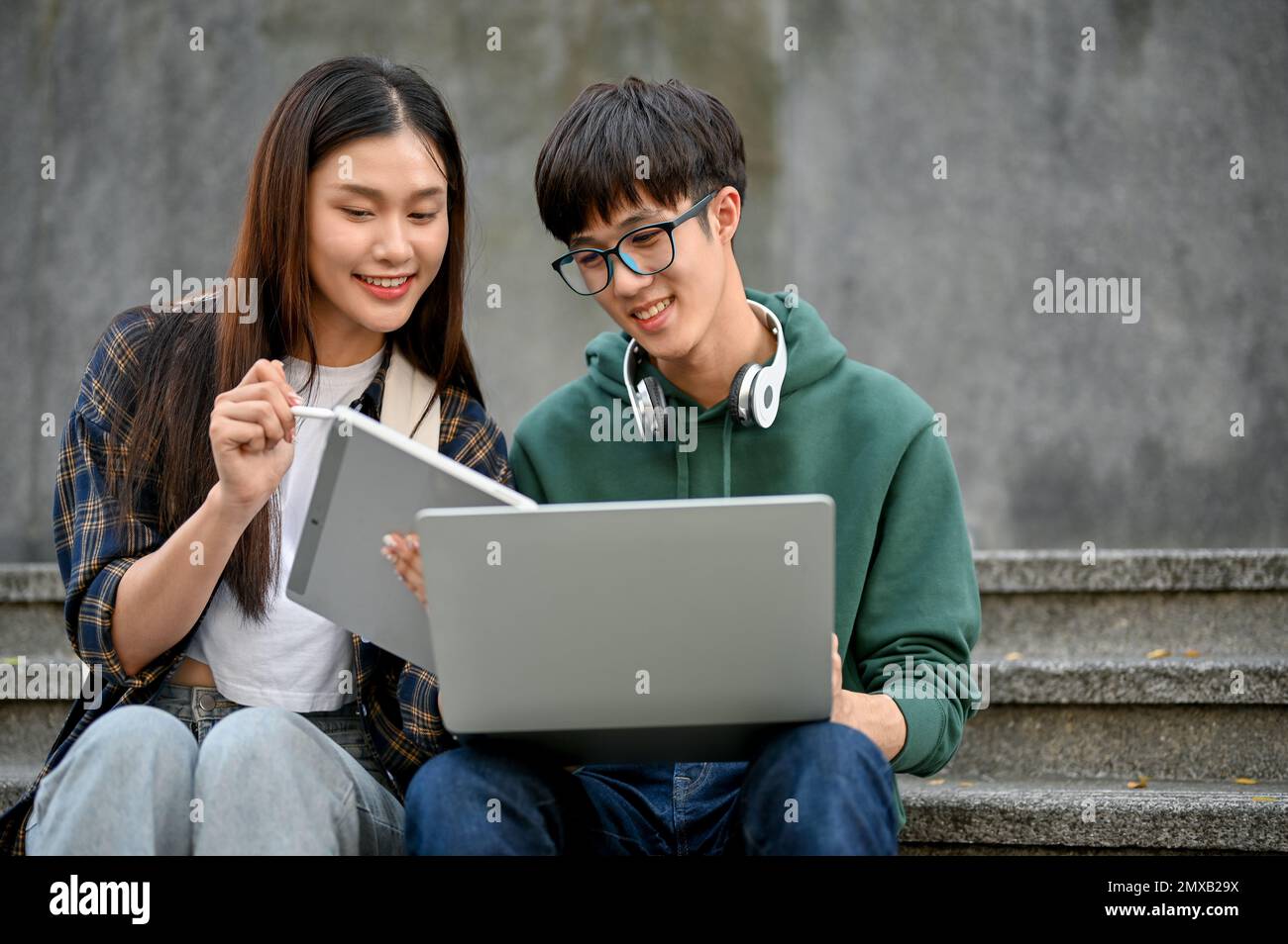 Smart young Asian male college student is using laptop, talking and ...