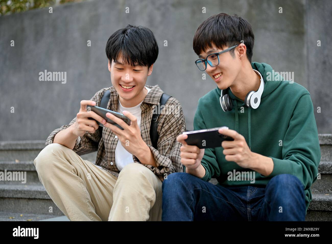 Happy young Asian man college student playing mobile game on his ...