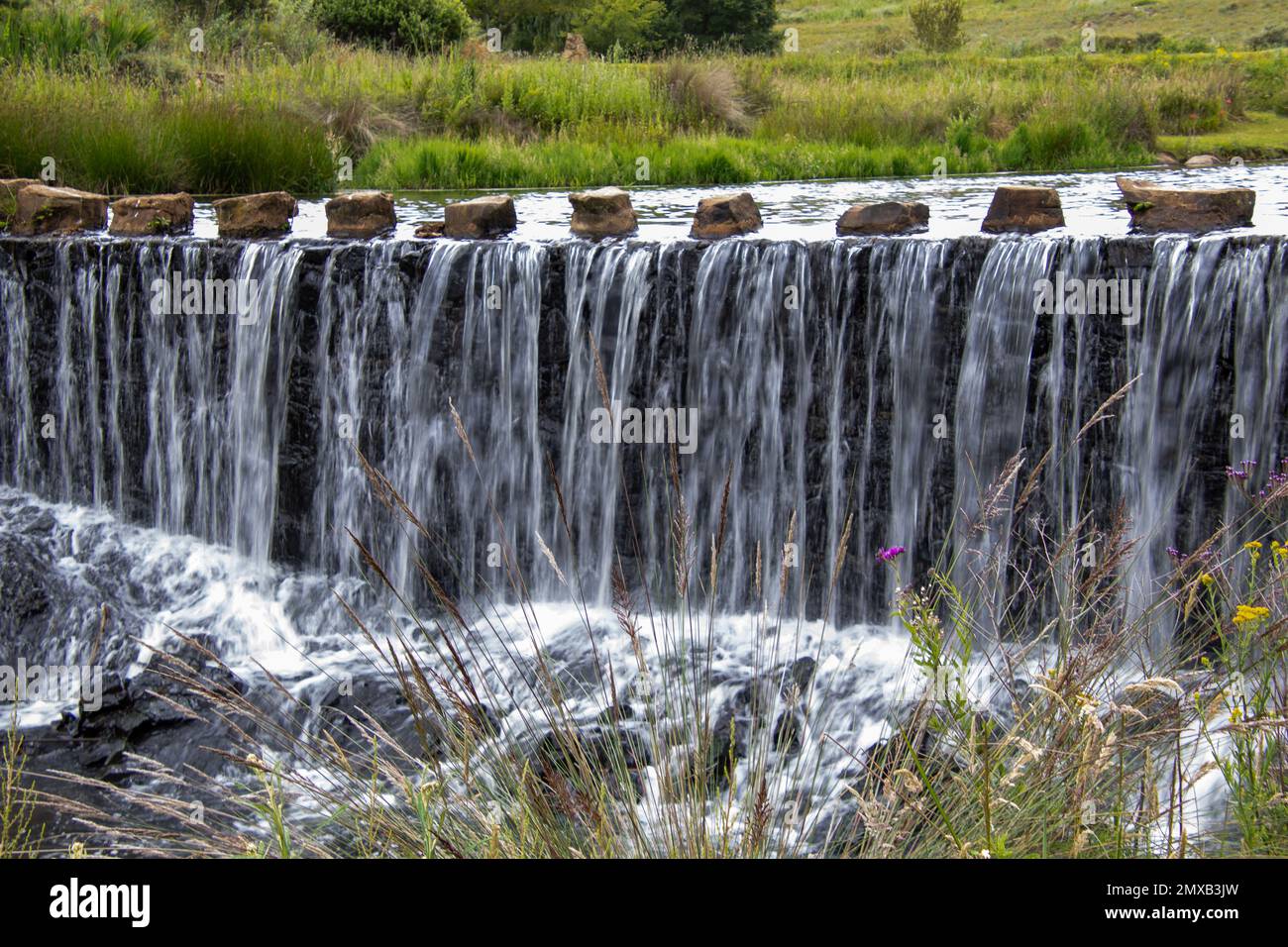 Slow shutter speed image of water running over a weir in a stream Stock ...