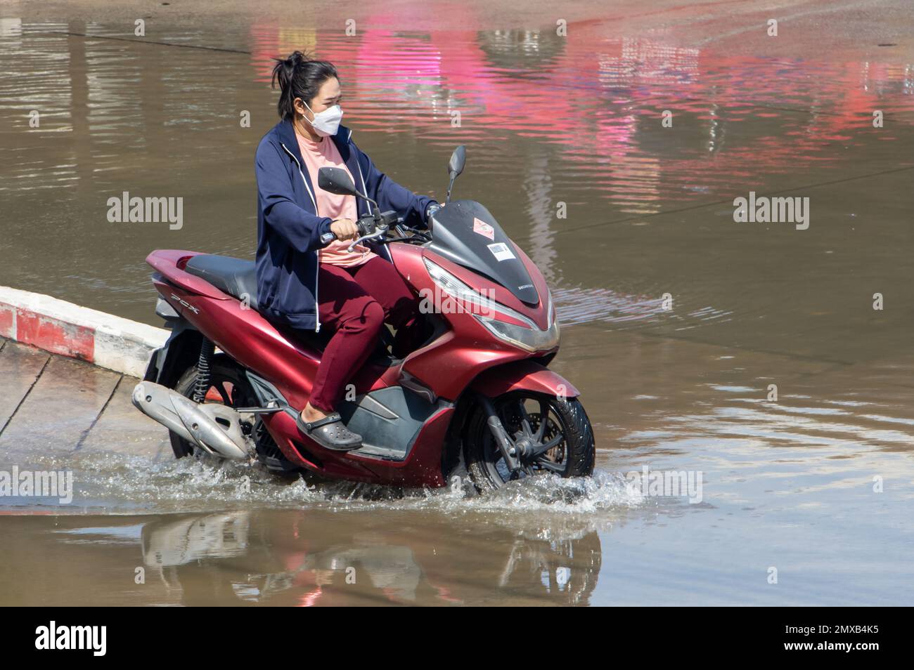 SAMUT PRAKAN, THAILAND, JAN 25 2023, A woman with face mask rides a ...
