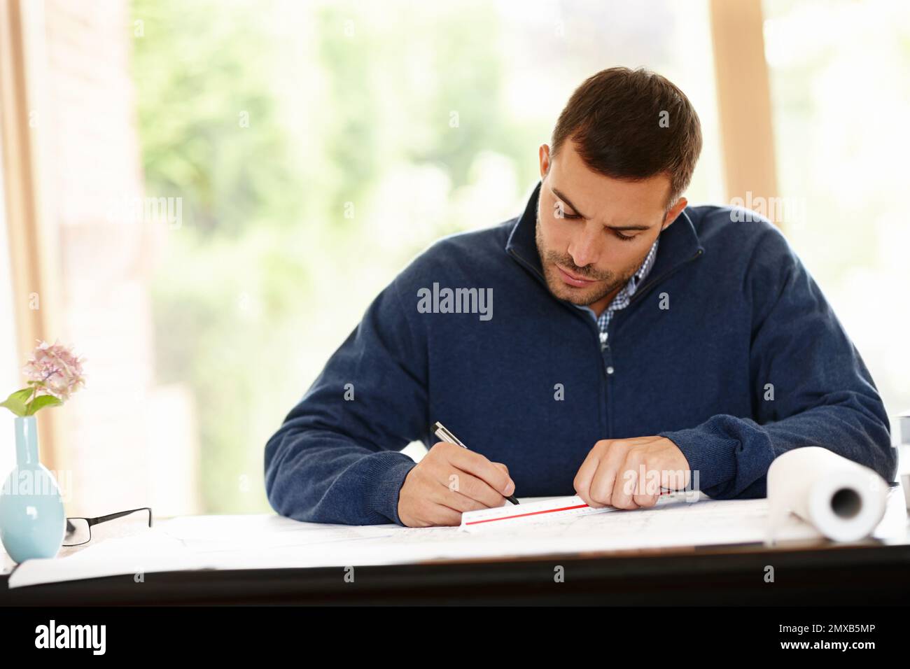 Working on the design of his dreams. a young man drawing up plans at ...