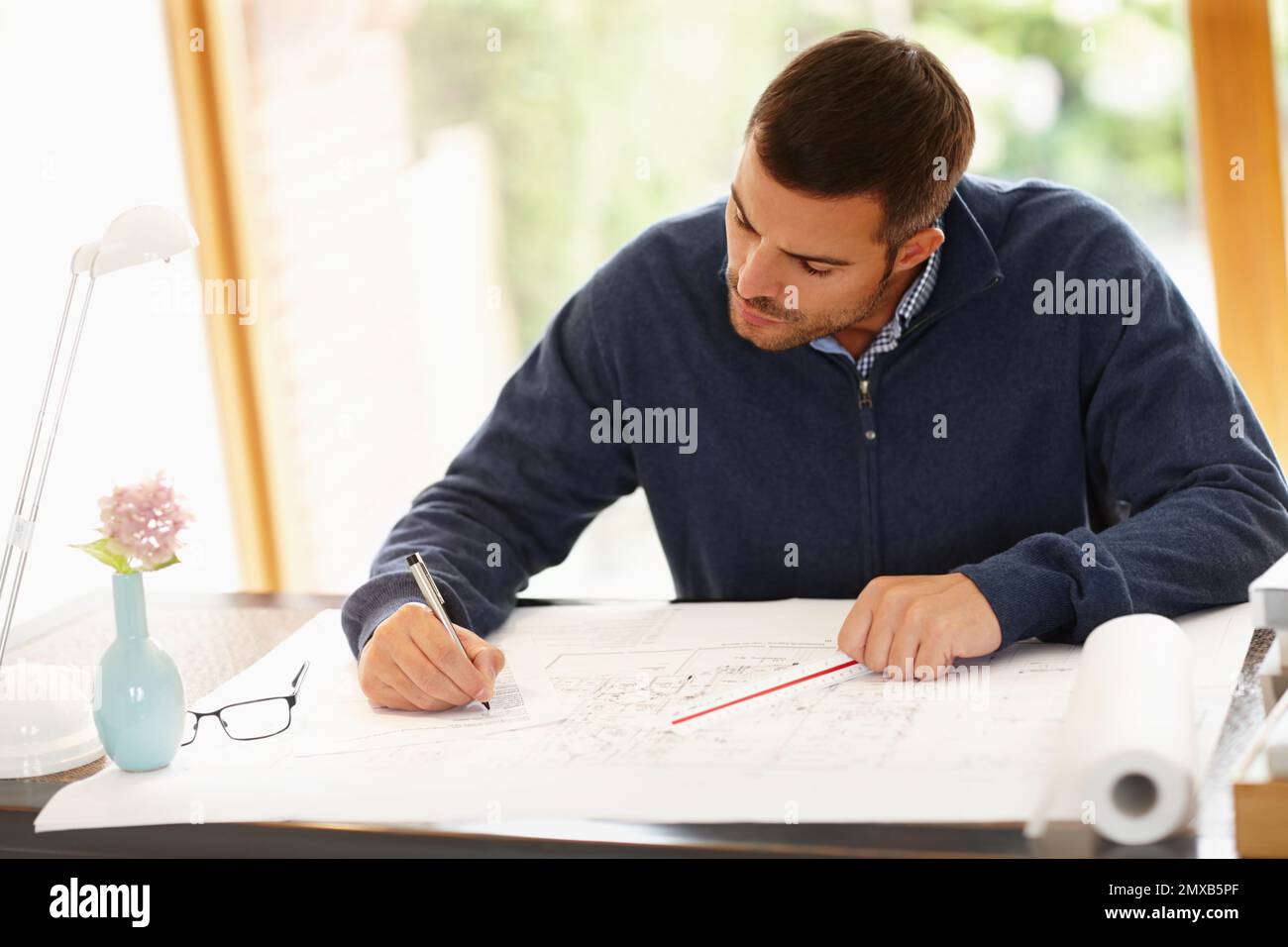 He plans to perfection. a young man drawing up plans at his desk Stock ...