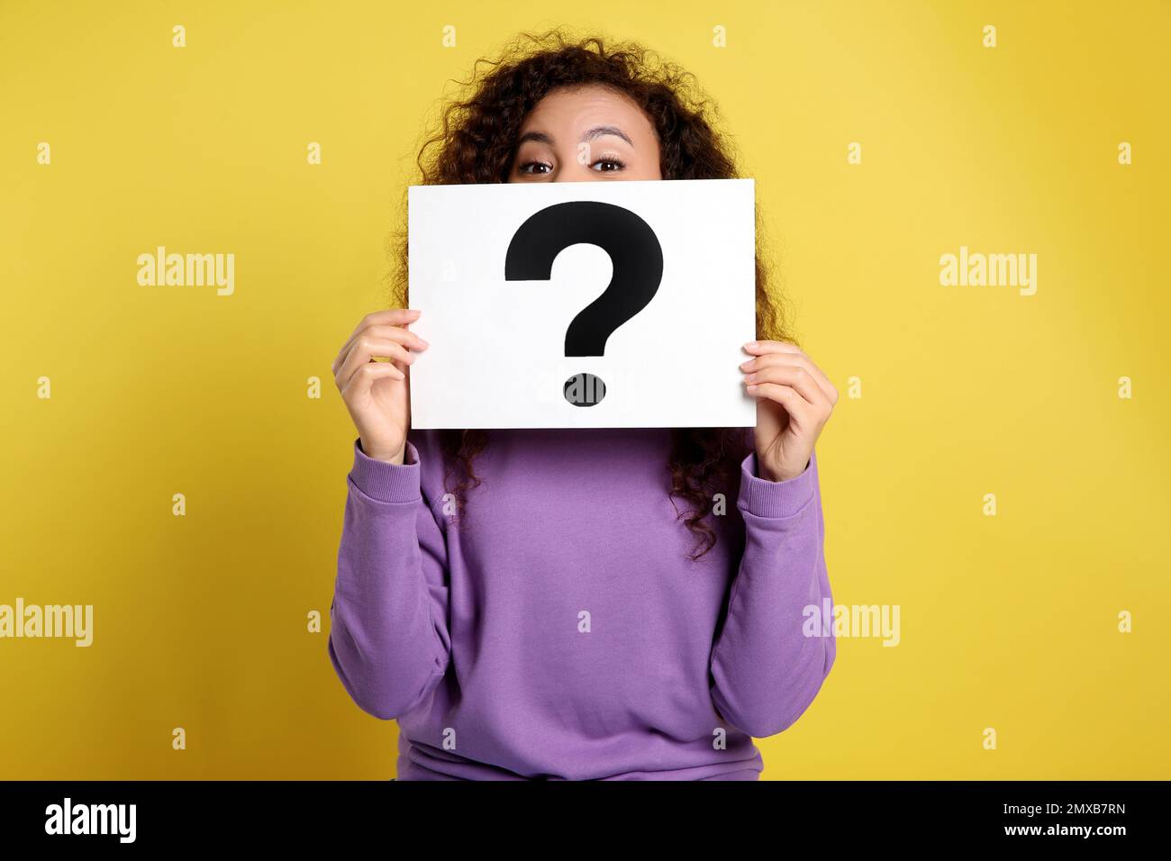 African-American woman with question mark sign on yellow background ...