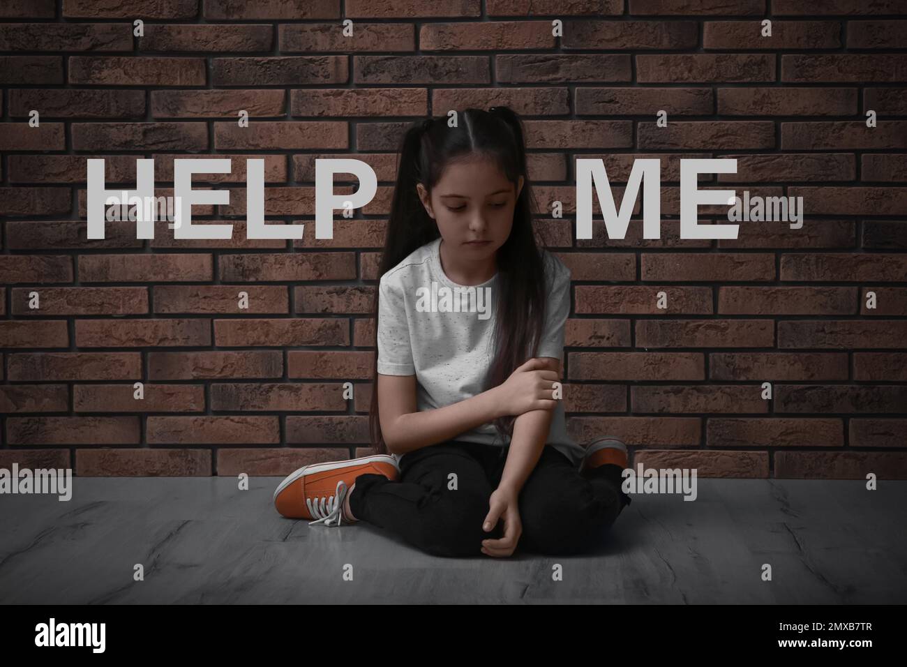 Sad little girl near brick wall and text HELP ME Stock Photo - Alamy