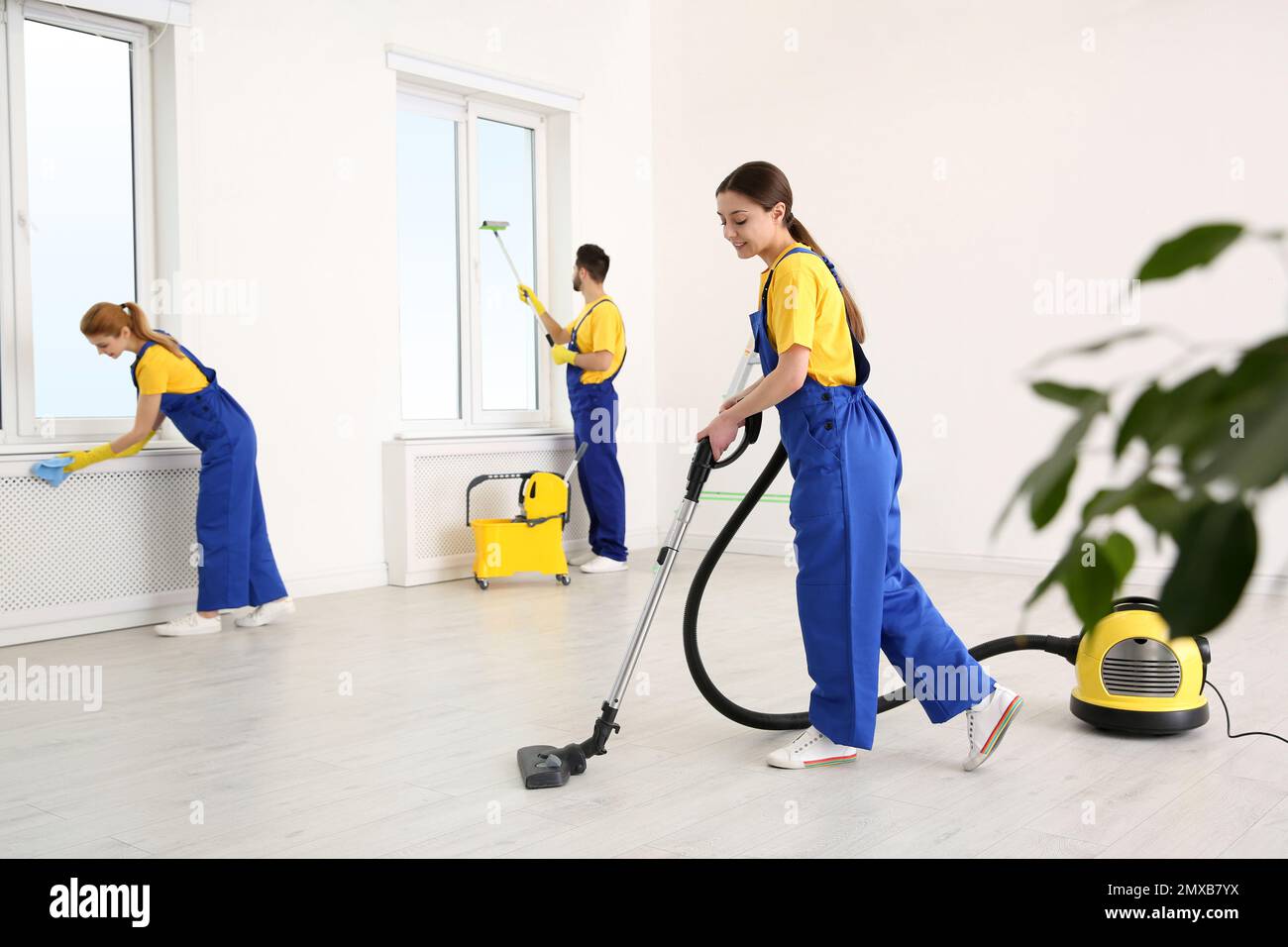 Team of professional janitors in uniforms cleaning room Stock Photo - Alamy