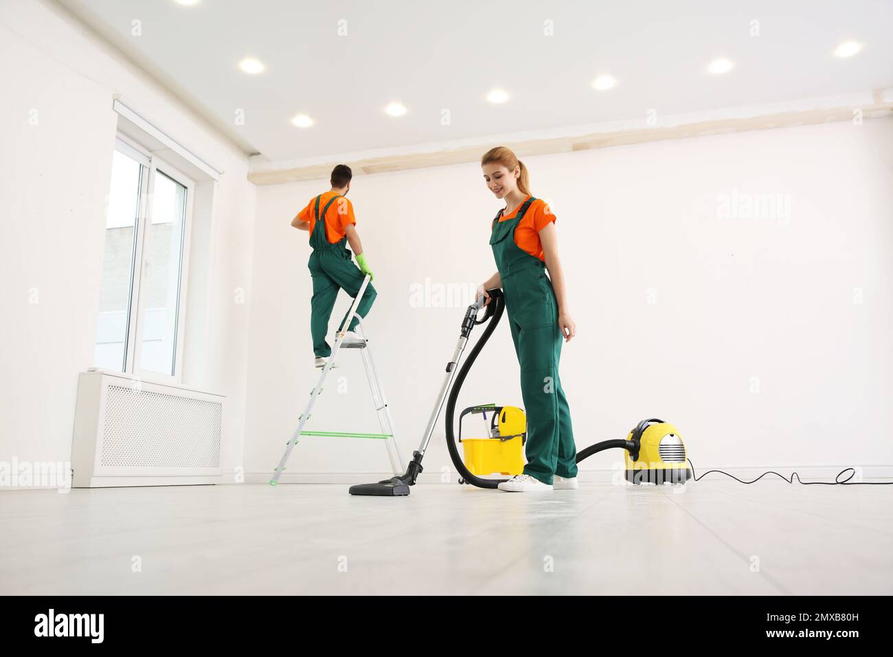 Professional young janitor vacuuming indoors. Cleaning service Stock ...