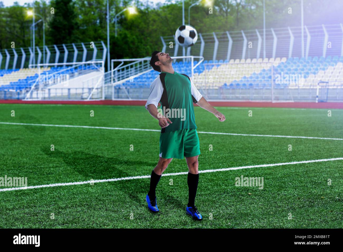 Young man in uniform playing football at stadium Stock Photo - Alamy