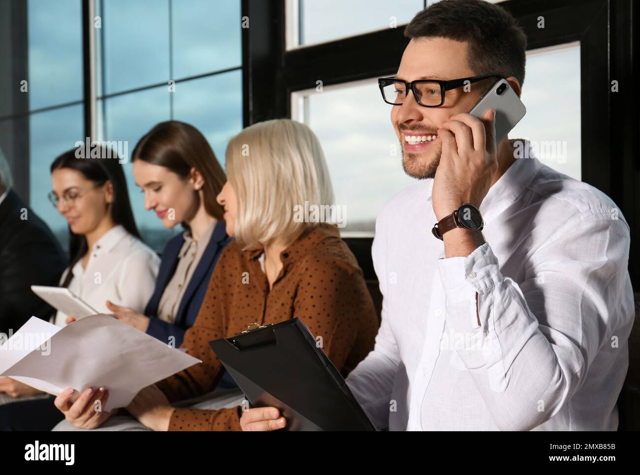 Man talking on phone while waiting for job interview in office hall ...