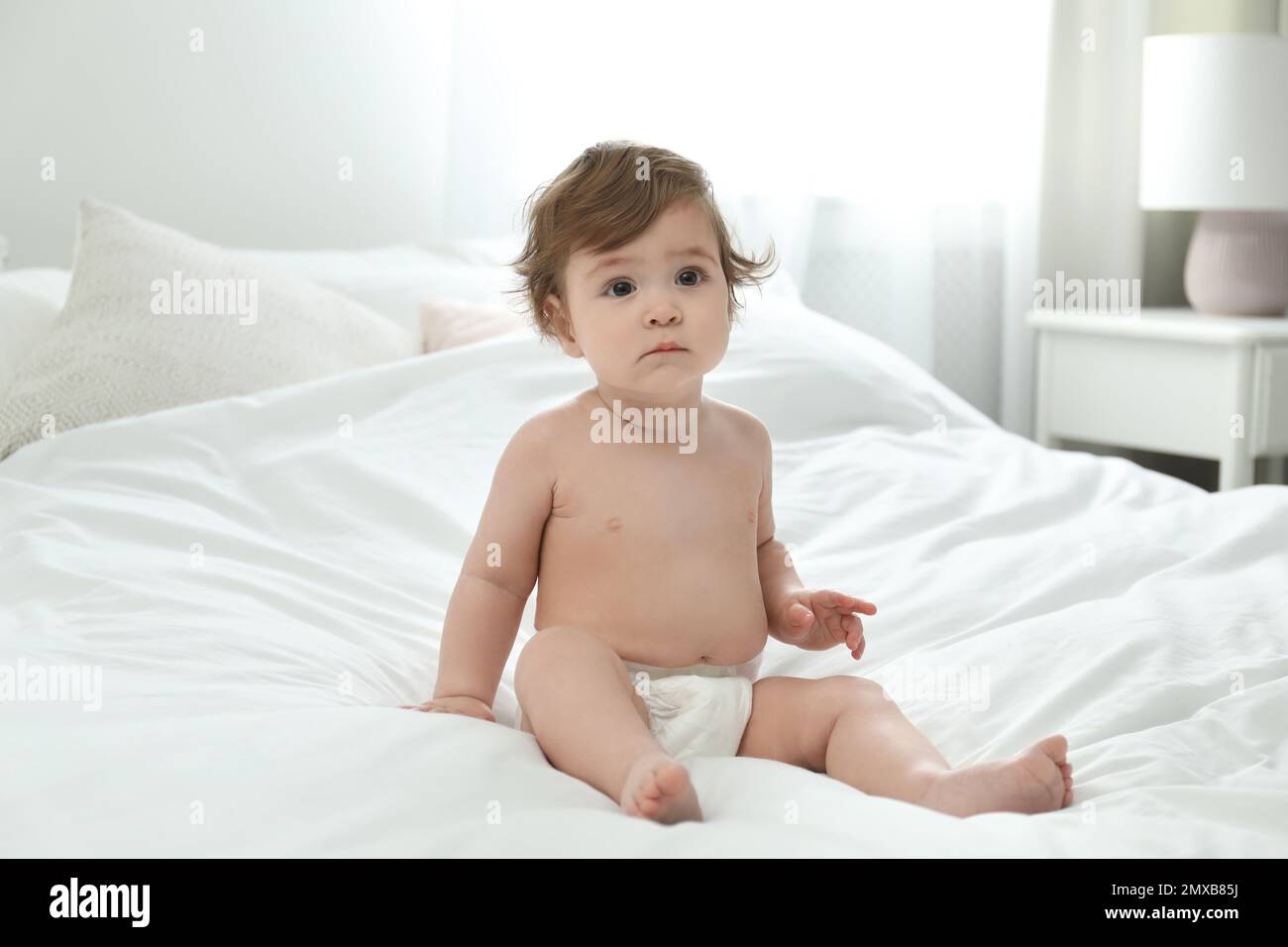 Cute little baby in diaper on bed Stock Photo - Alamy