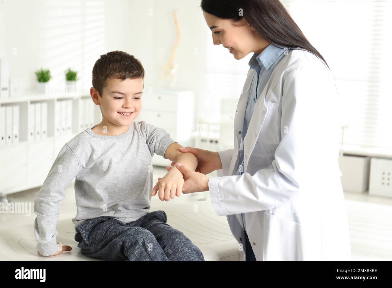 Professional orthopedist examining little patient's arm in clinic Stock ...
