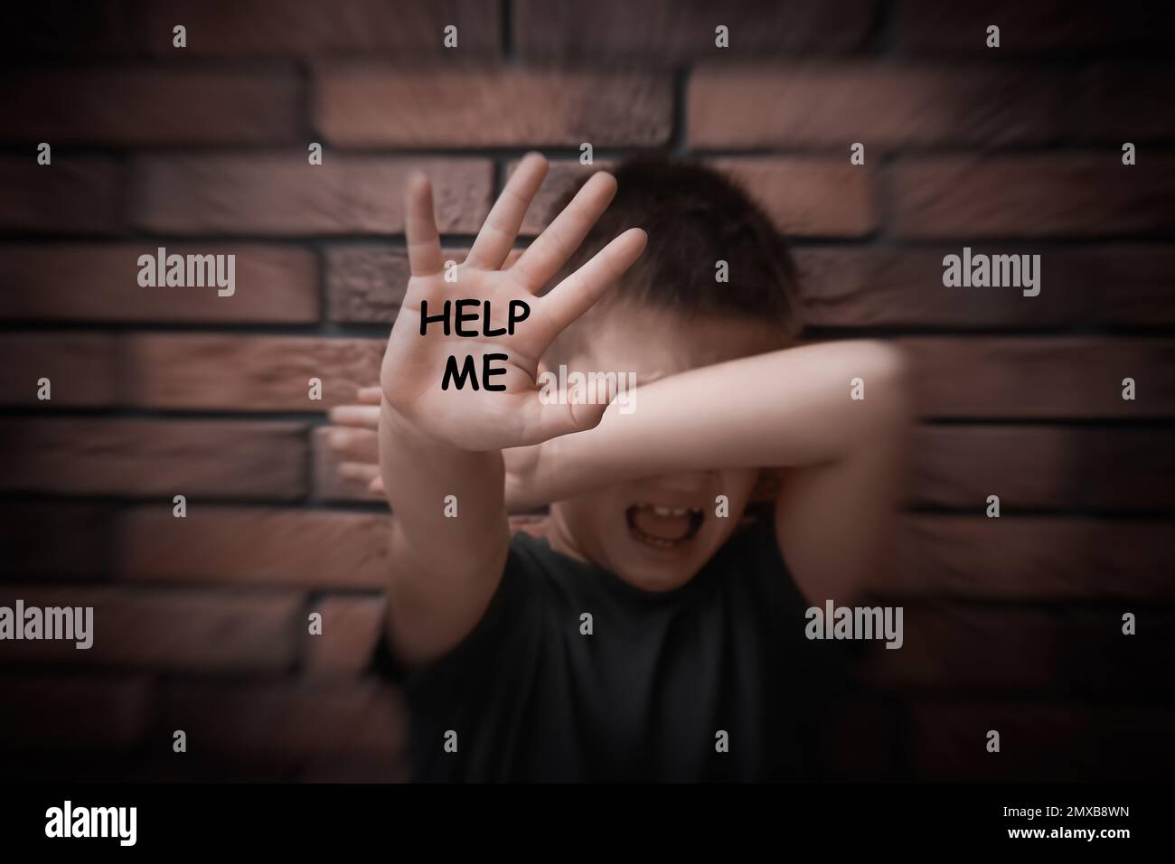 Scared little boy with text HELP ME on his hand near brick wall Stock ...