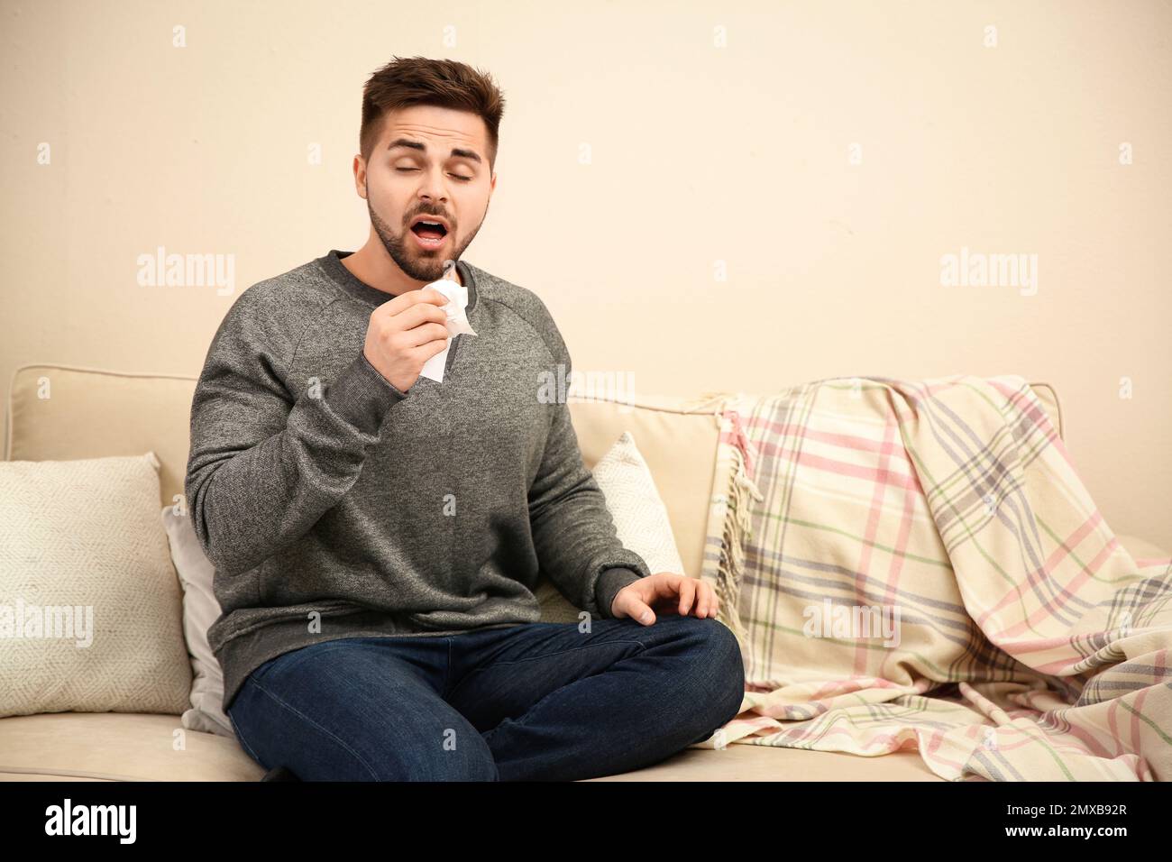 Sick young man sneezing at home. Influenza virus Stock Photo - Alamy
