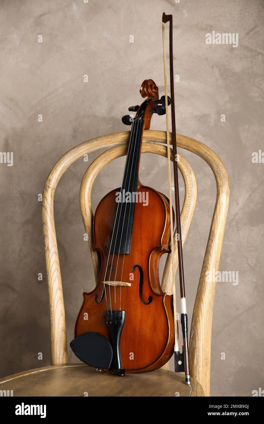 Classic violin and bow on chair against beige background Stock Photo ...