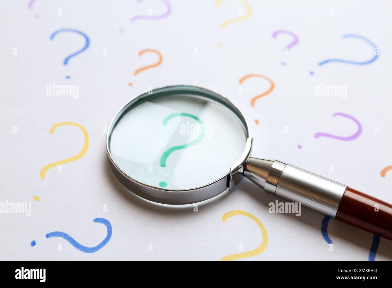Magnifying glass on sheet of paper with question marks. Search concept ...