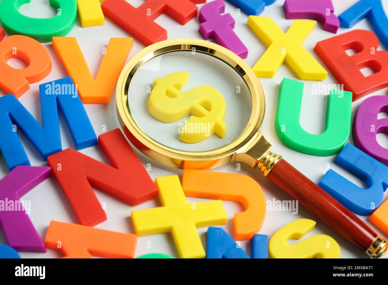 Magnifying glass over dollar sign surrounded by magnet letters on white ...