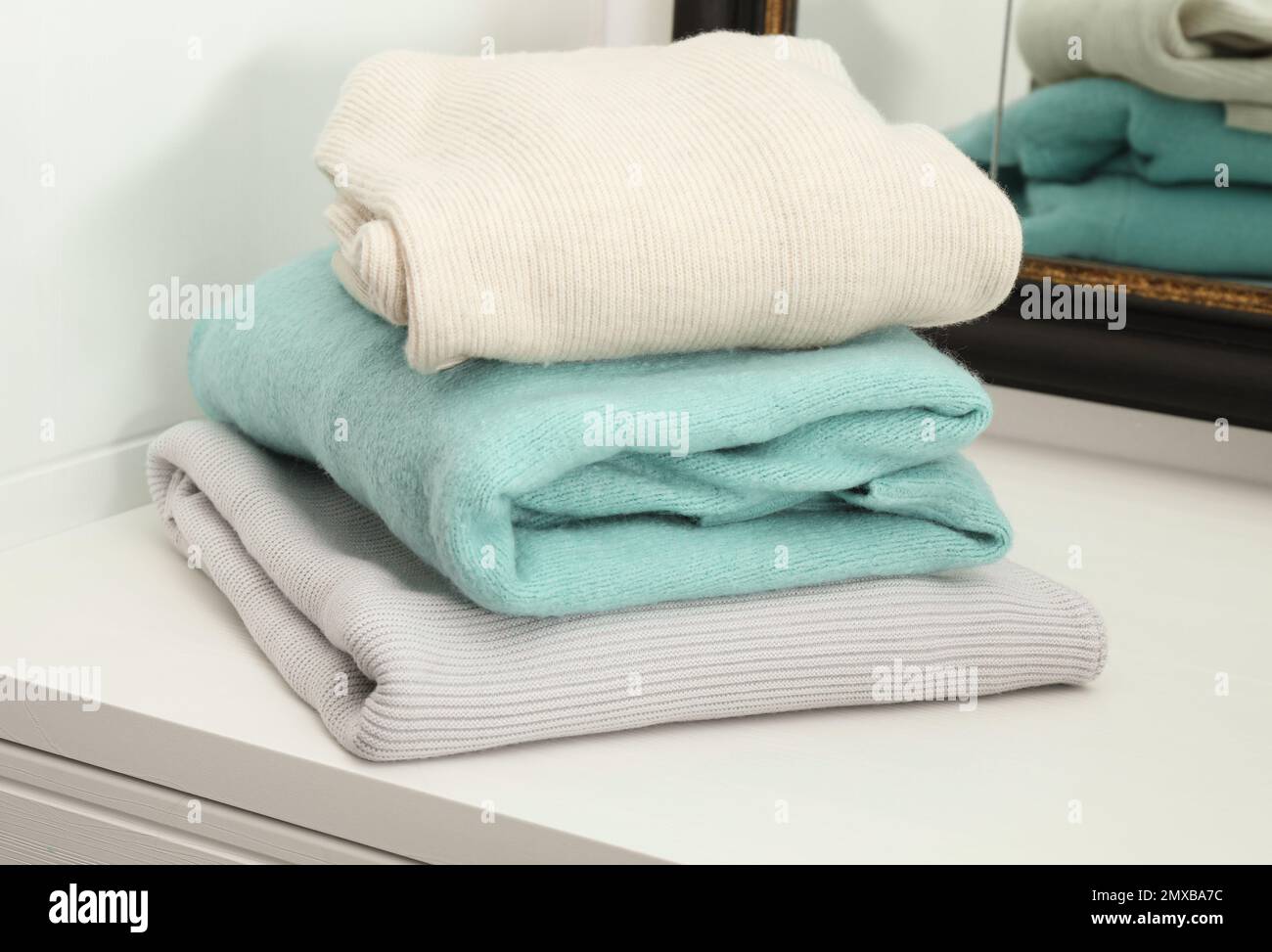 Stack of folded clothes on cabinet indoors Stock Photo - Alamy
