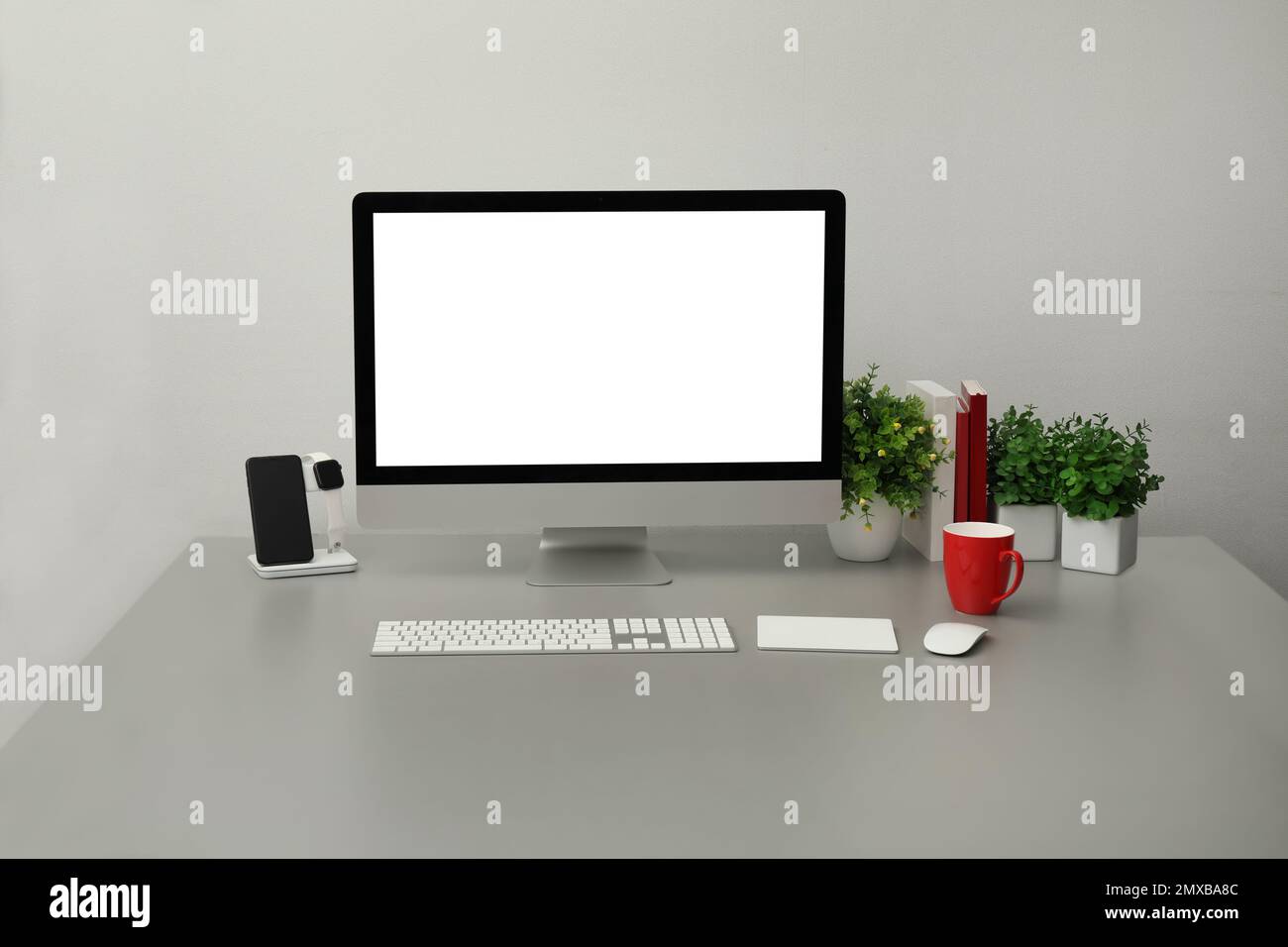 Modern workplace with computer, charging devices and houseplants ...