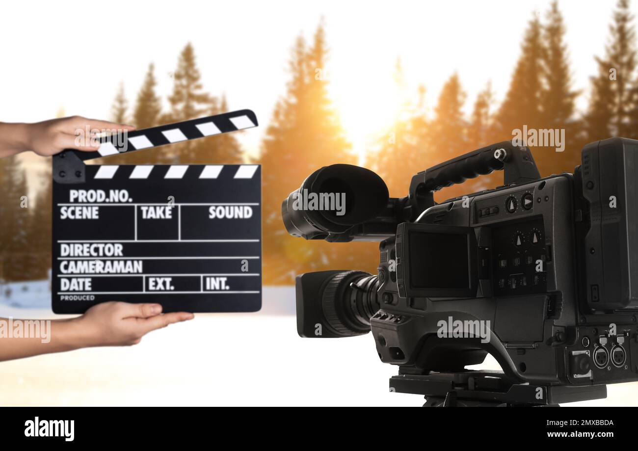 Modern video camera and assistant with clapperboard outdoors, closeup ...