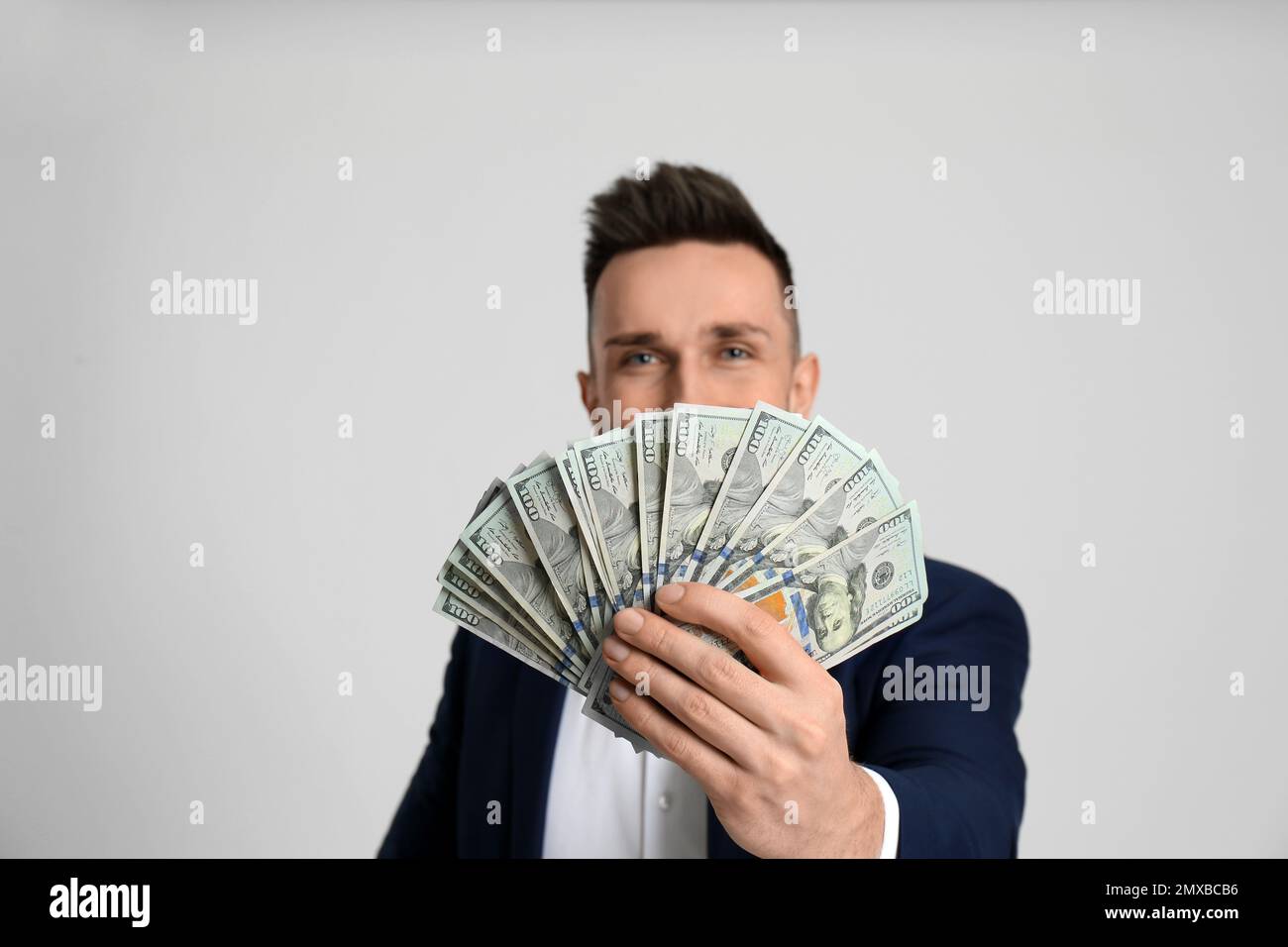 Happy man with cash money against light grey background, focus on hand ...