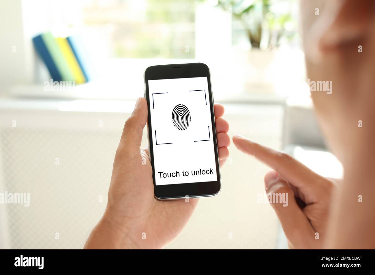 Man holding smartphone with fingerprint sensor indoors, closeup ...