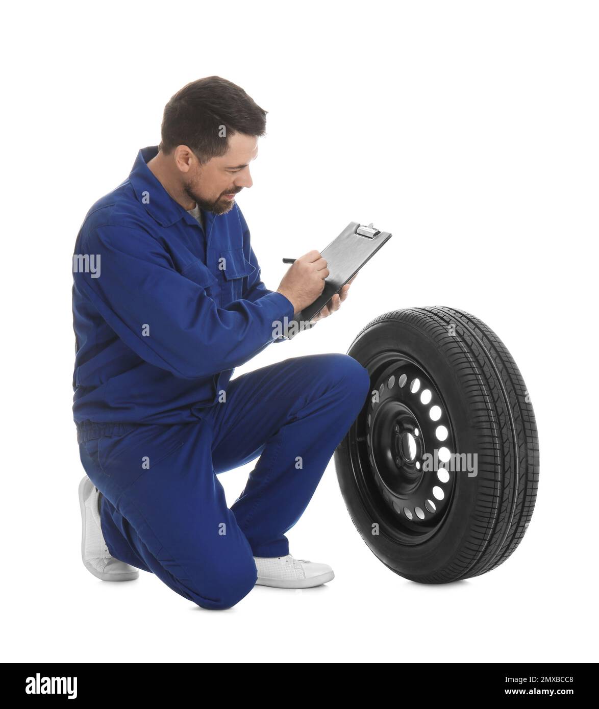 Professional auto mechanic with wheel and clipboard on white background ...