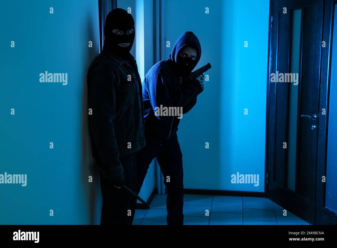 Dangerous criminals with gun and crow bar in hallway Stock Photo - Alamy