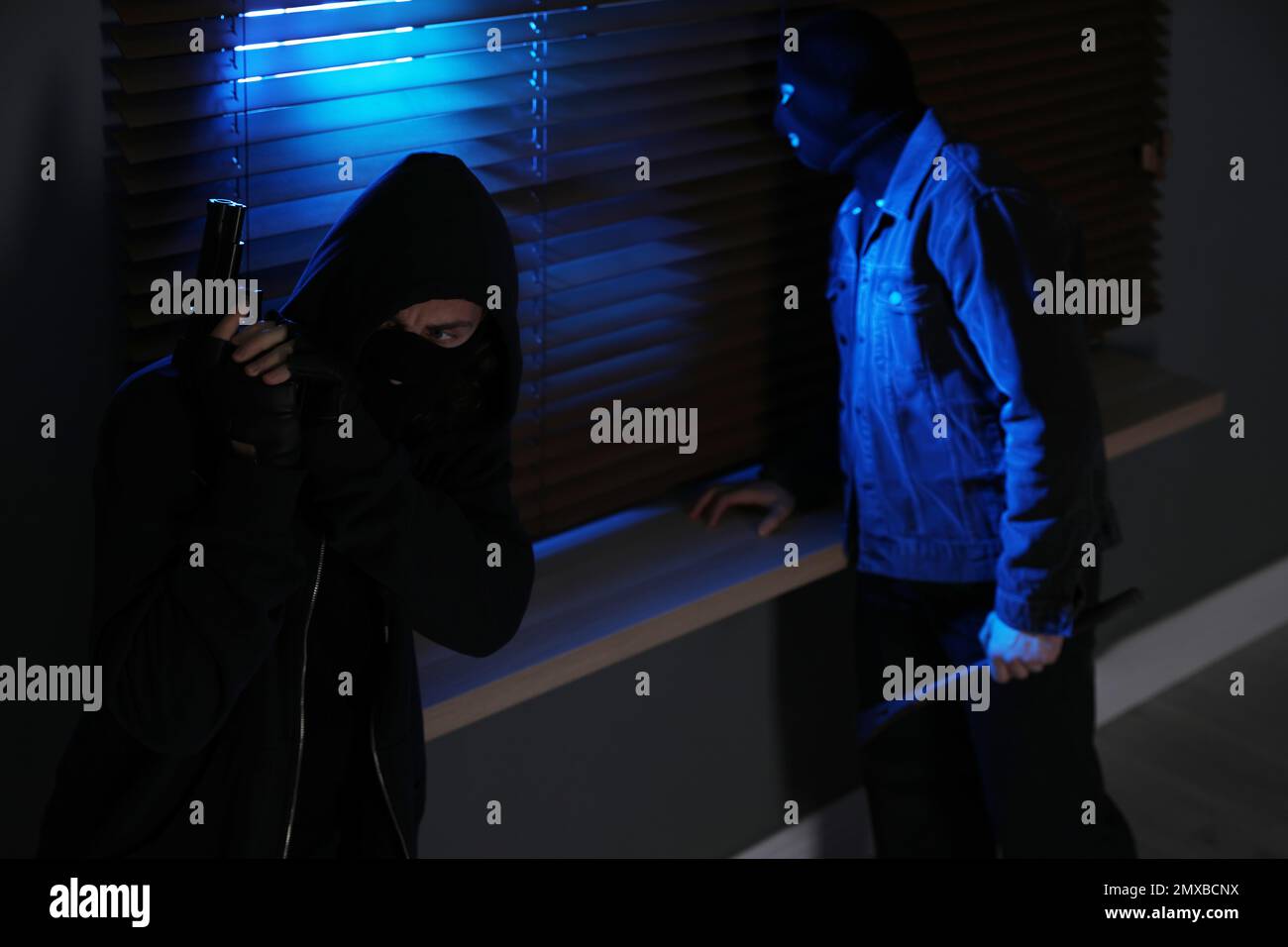 Dangerous criminals with gun and crow bar near window indoors Stock ...