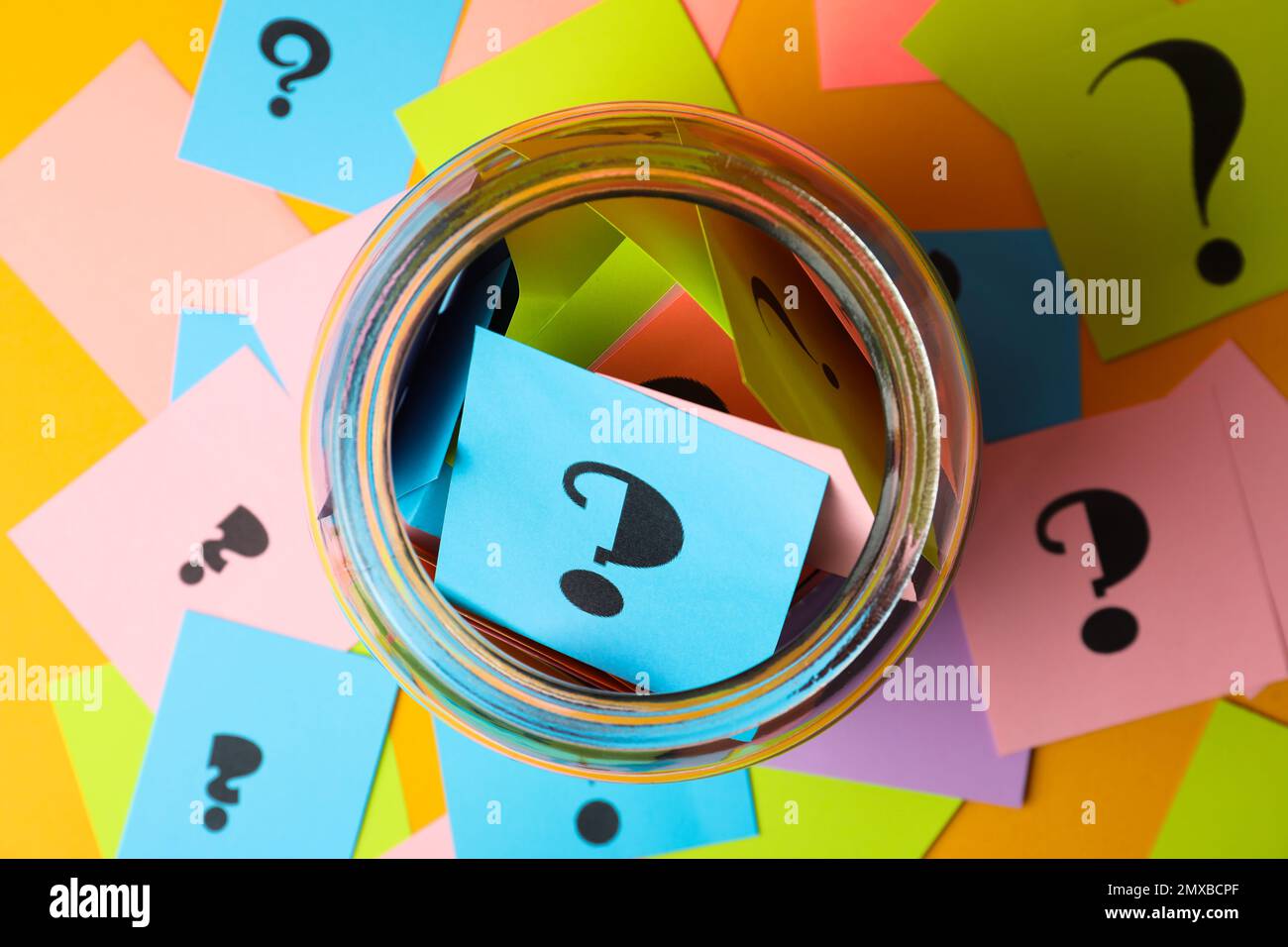 Colorful cards with question marks and glass jar on yellow background ...