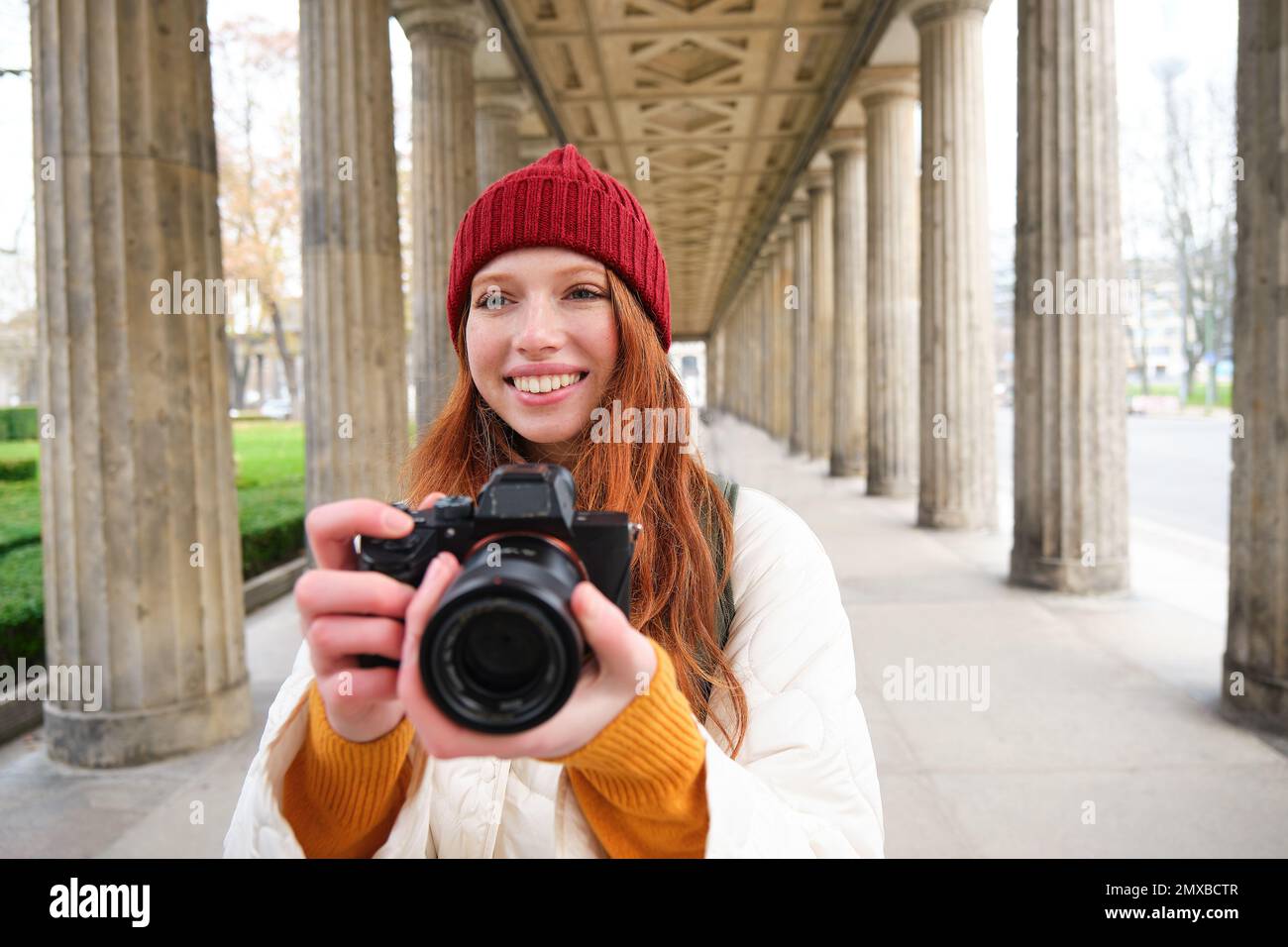 Smiling tourist photographer, takes picture during her trip, holds ...