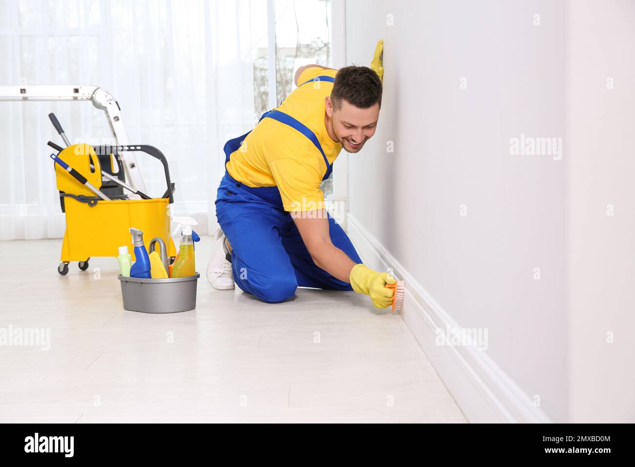 Professional janitor cleaning baseboard with brush after renovation ...