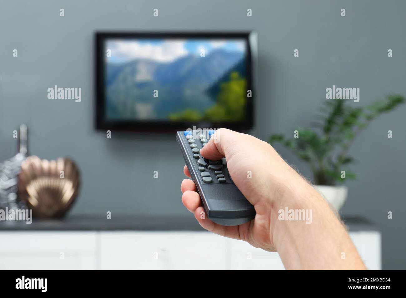 Man switching channels on TV set with remote control at home Stock Photo - Alamy