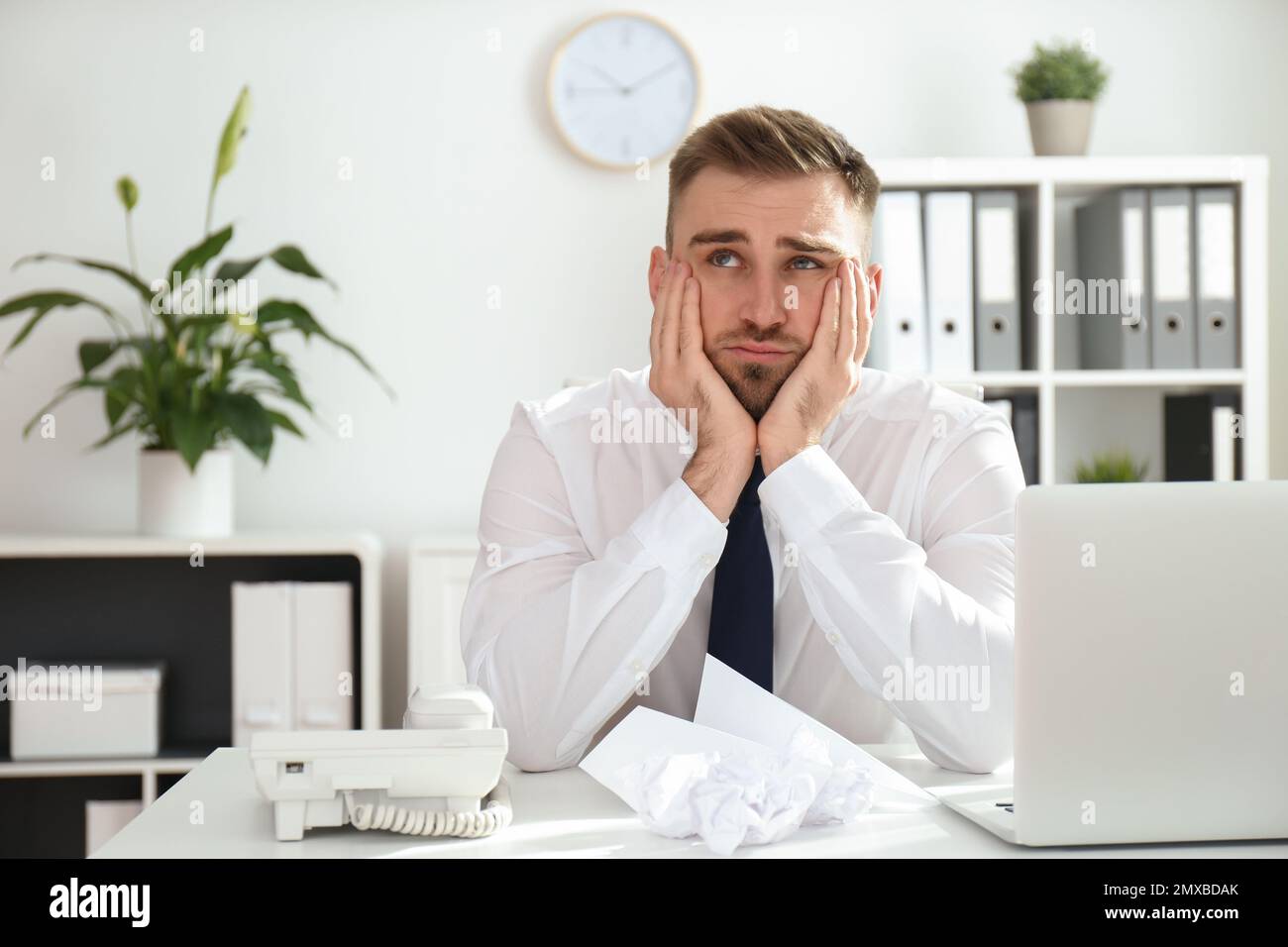 Lazy young man wasting time at messy table in office Stock Photo - Alamy