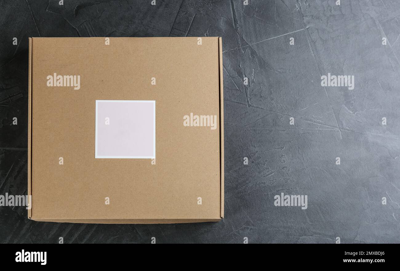 Closed cardboard box on grey stone table, top view. Space for text ...