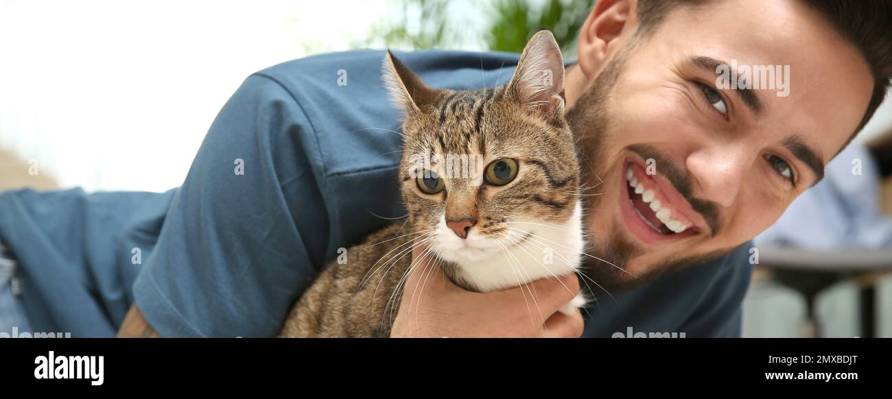 Happy young man with cat at home. Banner design Stock Photo - Alamy