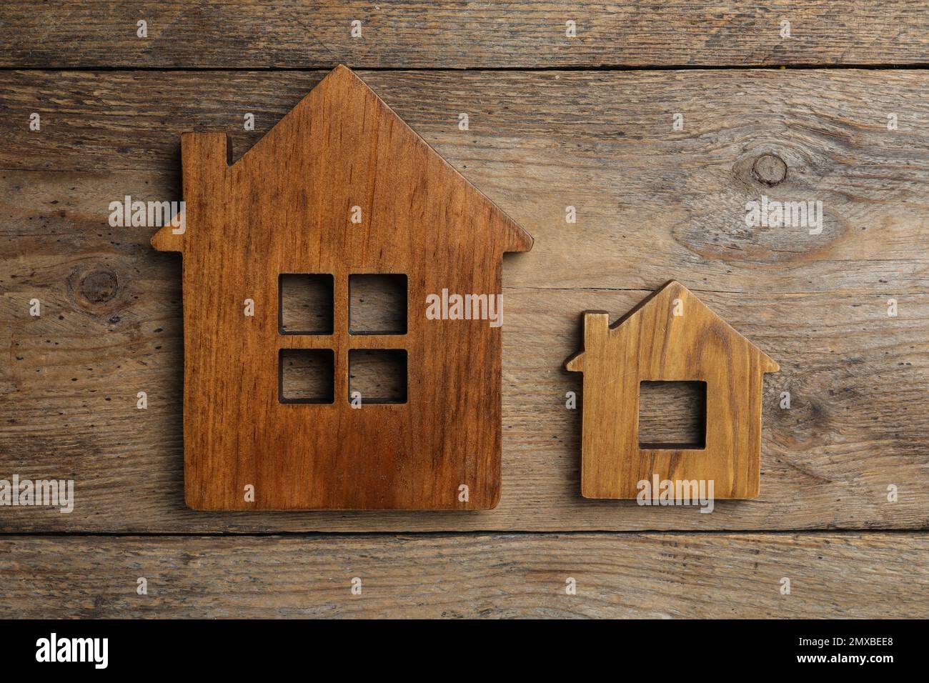 Small and big house figures on wooden background, flat lay. Pareto ...