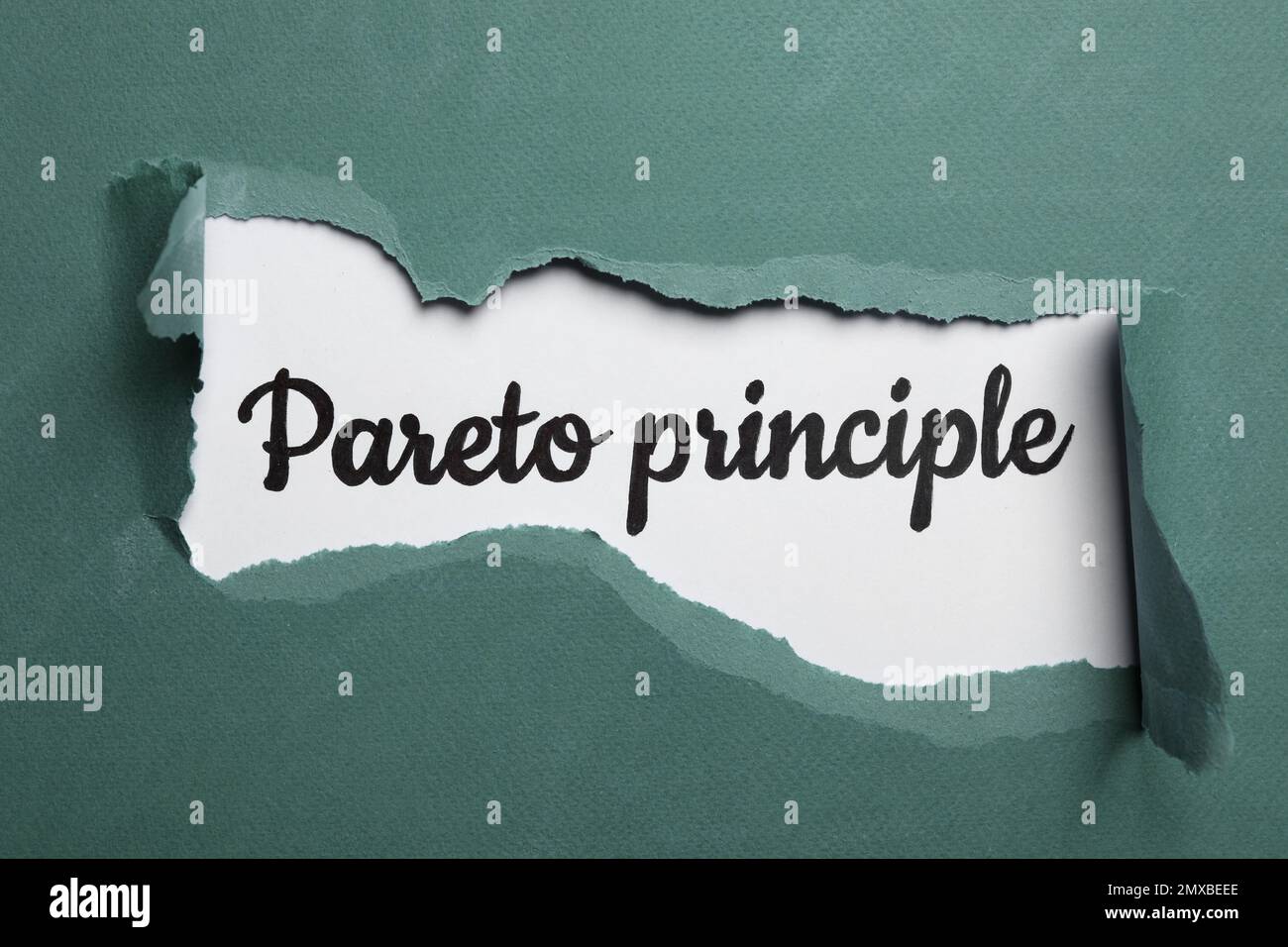 Words PARETO PRINCIPLE on white background, view through hole in green ...
