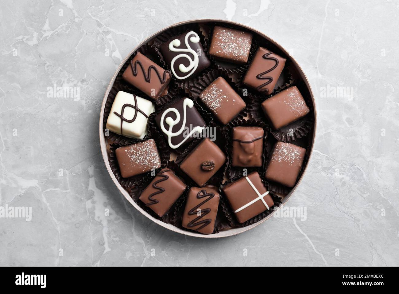 Box with tasty chocolate candies on light grey marble table, top view ...