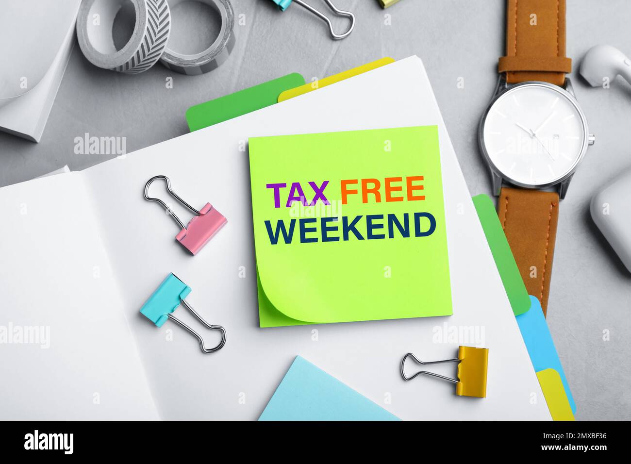 Note with text TAX FREE WEEKEND and stationery on grey table, flat lay ...