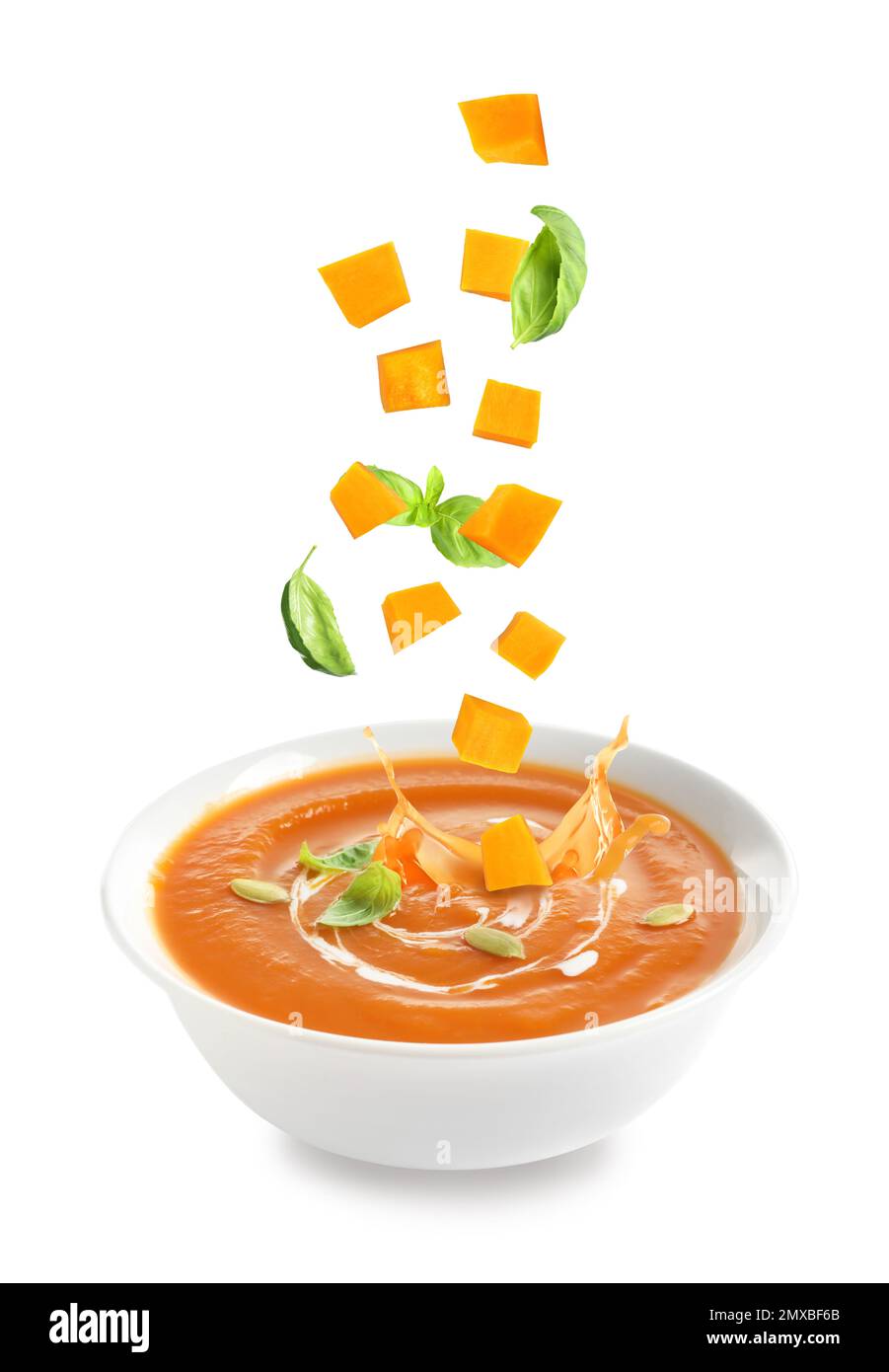 Ingredients falling into bowl of homemade pumpkin soup on white ...